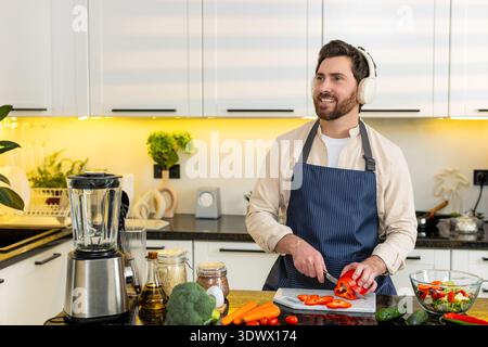 Middle-aged man happily chopping red pepper for fresh salad while ...