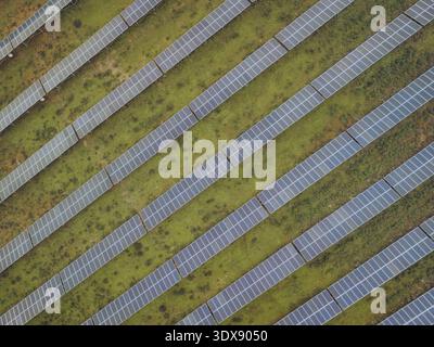 Solar panels stand against green mountains and blue sky at a ...