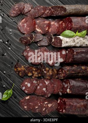Sliced cured meat arranged on round wooden board. Bright red cherry ...
