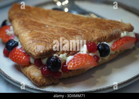 Croissant filled with cream and fresh berries on a plate Stock Photo ...