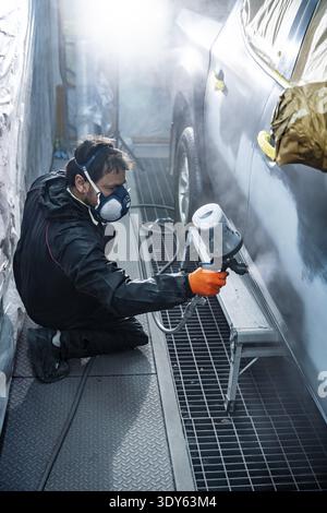 Worker in protective suit applying white paint to a boat interior using ...