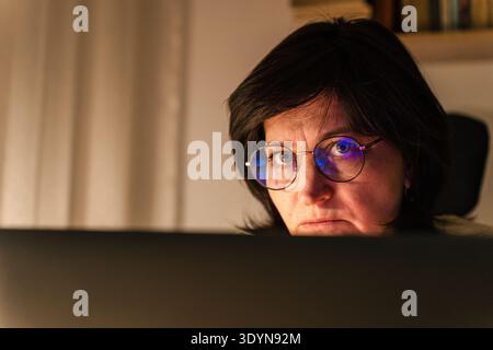 Woman in glasses concentrating on work, writing in a notebook and ...