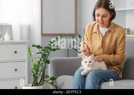 Young woman applying spot-on parasite treatment to cat's neck at home ...