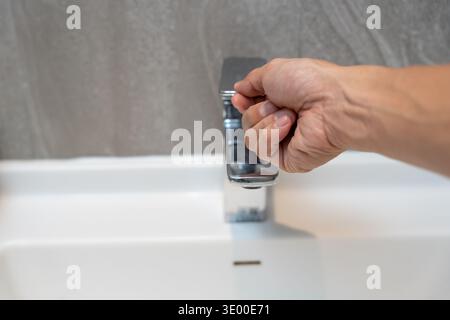 Save water. Man keeps turning off the running water in the bathroom to ...