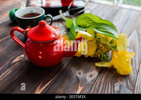 A yellow teapot sits on a wooden surface, surrounded by dried flower ...