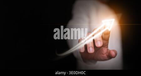 Hand pointing to a glowing upward arrow and stock market chart overlay ...