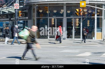 People cross an intersection in front of a billboard showing a portrait ...