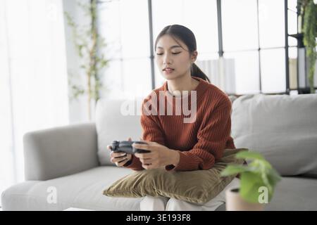 Asian woman play video game with headphones and controller relax on ...
