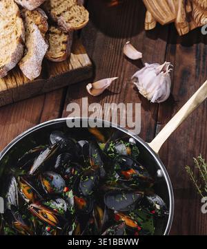 Mussels in savory sauce served in oval white dish. Background features ...