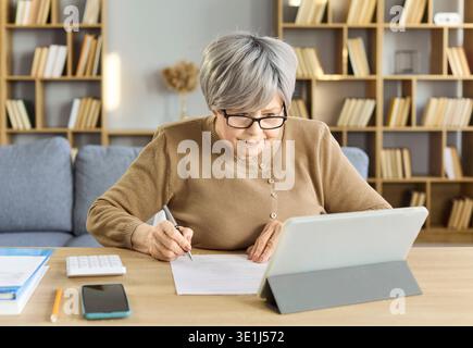 Senior woman doing online banking, paying domestic utility bills at ...