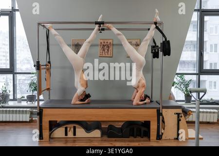 Two modern wooden Pilates reformer machines stand ready in a bright ...