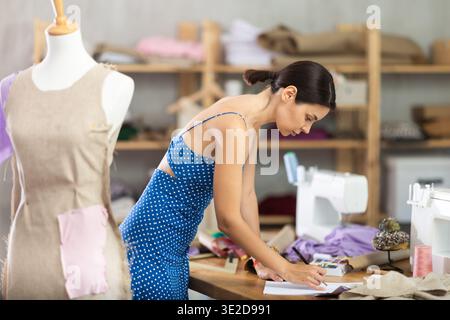 Young woman seamstress draws sketch on paper Stock Photo - Alamy