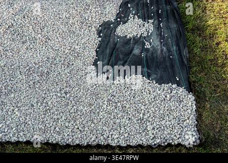 Gravel aggregate covering white landscape fabric, forming a drainage ...