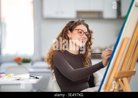 Young woman artist expressing creativity by painting on a canvas ...
