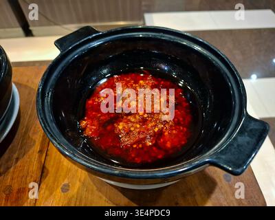 Vibrant red chili paste in white ceramic bowl surrounded by fresh green ...