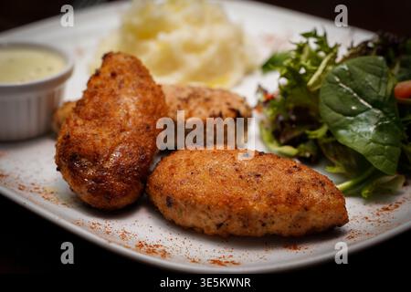 Crispy golden brown breaded cutlets on textured white plate garnished ...