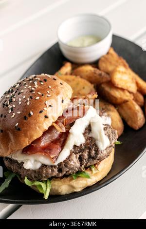 Gourmet wagyu beef burger wirh bacon, cheese and wedge fries on outdoor ...