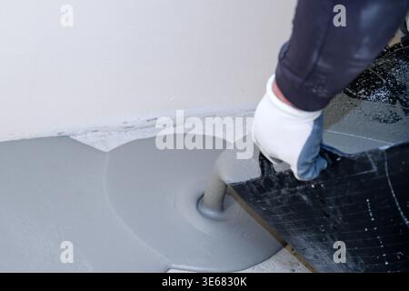 Worker pours concrete from container into wooden mold at construction ...