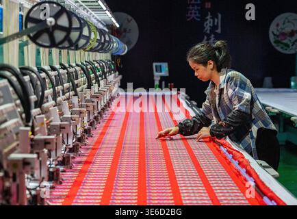A worker is working in a digital embroidery production workshop in ...