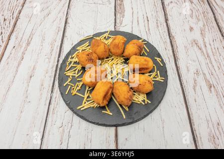 A plate of Iberian ham croquettes, darker in color and with large ...