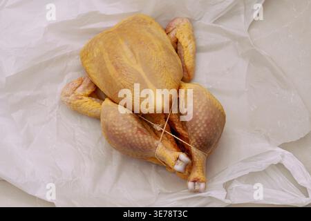 Raw chicken on parchment paper atop wooden cutting board surrounded by ...