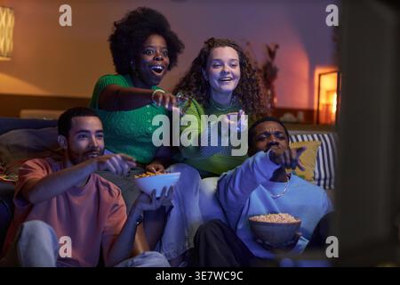 People watch a screen in a dimly lit venue with colorful lights and a ...