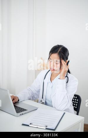 Asian women doctor working from home using laptop computer writing ...