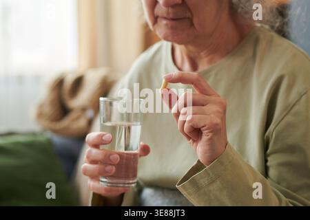 Senior woman taking daily medication pill for health and wellness with ...