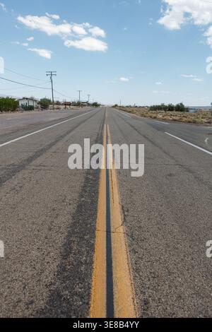 A straight two lane highway stretches through a remote desert canyon ...