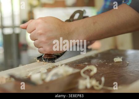 Asian man owner a small furniture business is preparing wood for ...
