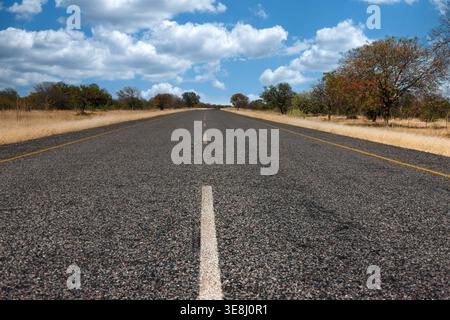 A straight two lane highway stretches through a remote desert canyon ...