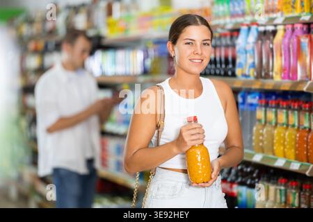 Young woman choosing soda in grocery store Stock Photo - Alamy