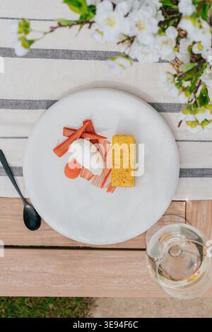 A portion of orange cheesecake with a strawberry decoration served in a ...