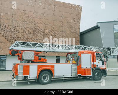 A fire truck with an extended ladder is parked on a street in front of ...
