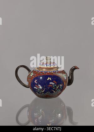 A yellow teapot sits on a blue wooden surface. A pile of dried tea ...
