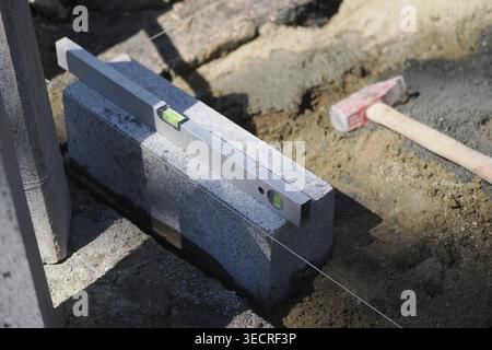 Workers place concrete blocks in row on building site surrounded by ...