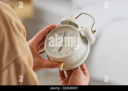 Woman changing alarm clock for daylight saving time at home, closeup ...