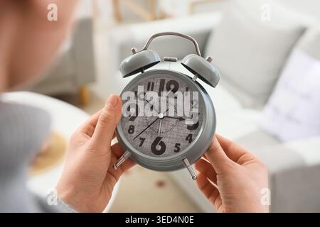 Woman changing alarm clock for daylight saving time at home, closeup ...