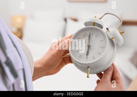 Woman changing alarm clock for daylight saving time at home, closeup ...