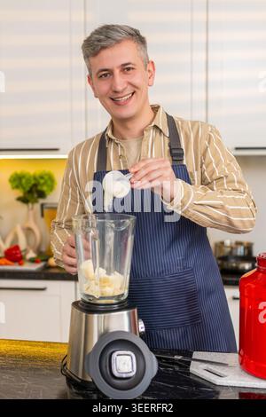 Middle-aged man adds protein powder into shaker with milk smiling for ...