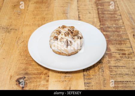 A round iced pastry topped with cookie crumbles and white drizzle sits ...
