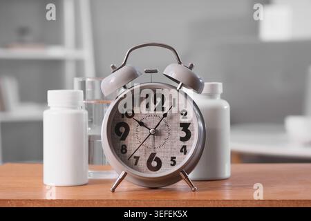Alarm clock with pill bottles on table in room, closeup Stock Photo - Alamy