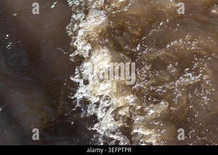 Dynamic stream water with frothy rapids, reflecting sunlight and ...