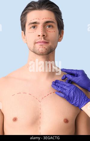 Plastic surgeon with scalpel and markings on young man's face against ...