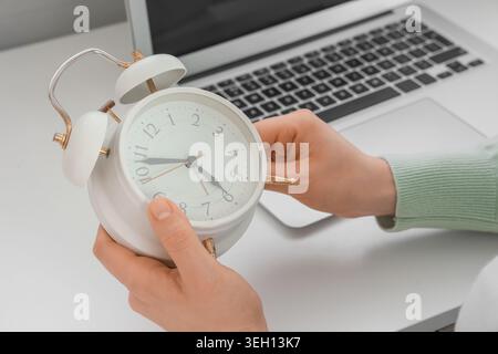 Female hands changing alarm clock for daylight saving time at home ...