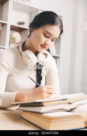 Asian woman studying with laptop and writing in notebook at home Stock ...