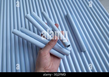 Hand holding white plastic pipes against a background of more pipes ...
