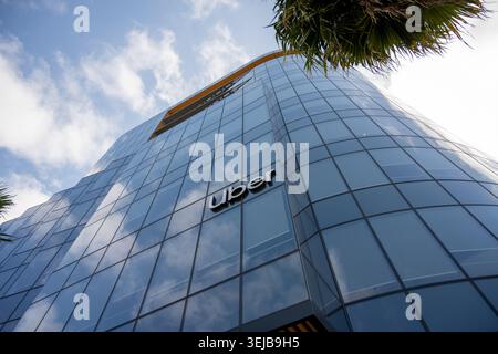 Exterior of modern glass building with Uber logo against blue sky and ...
