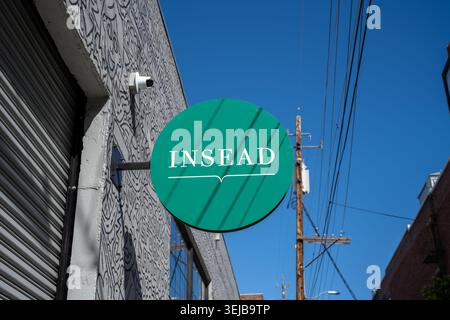 Round green INSEAD sign hanging on patterned gray building wall in ...