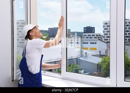 Professional worker examining window after installation indoors Stock ...